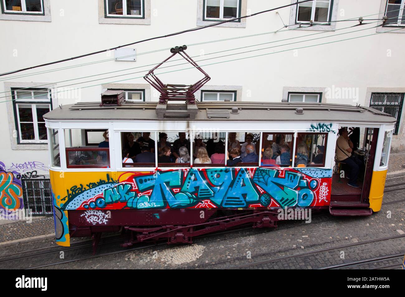 Side view of a famous tram of Lisbon, Portugal with colourful graffiti ...