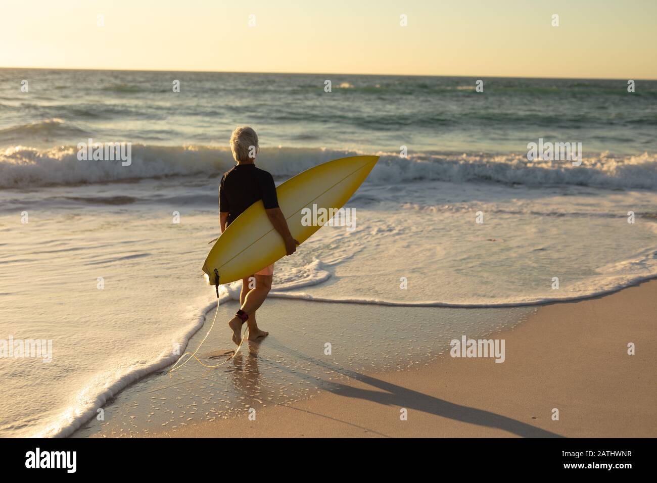 Old woman with a surfboard at the beach Stock Photo - Alamy