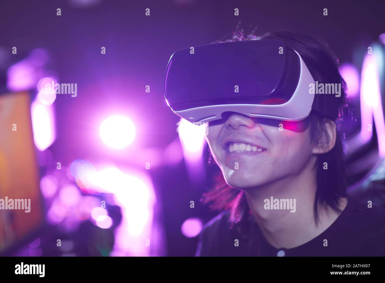 Head and shoulders portrait of young Asian man wearing VR headset while ...