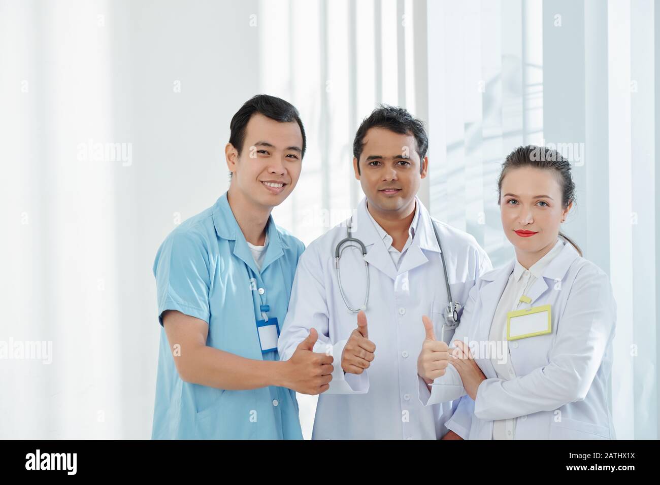 Happy healthcare workers in uniform and showing thumbs-up and smiling ...