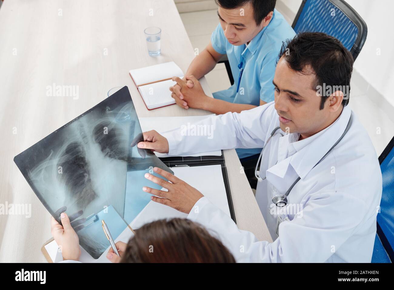 Pulmonologist discussing lungs x-ray of patient with his team and ...