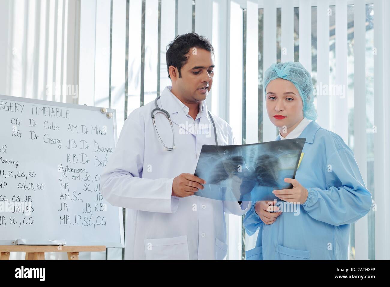 Chief doctor and surgeon discussing chest x-ray of patient suspected of ...