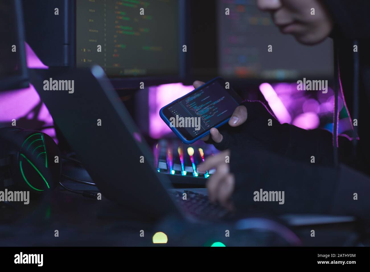 Close up of unrecognizable cyber security hacker wearing hood while working on programming in ...