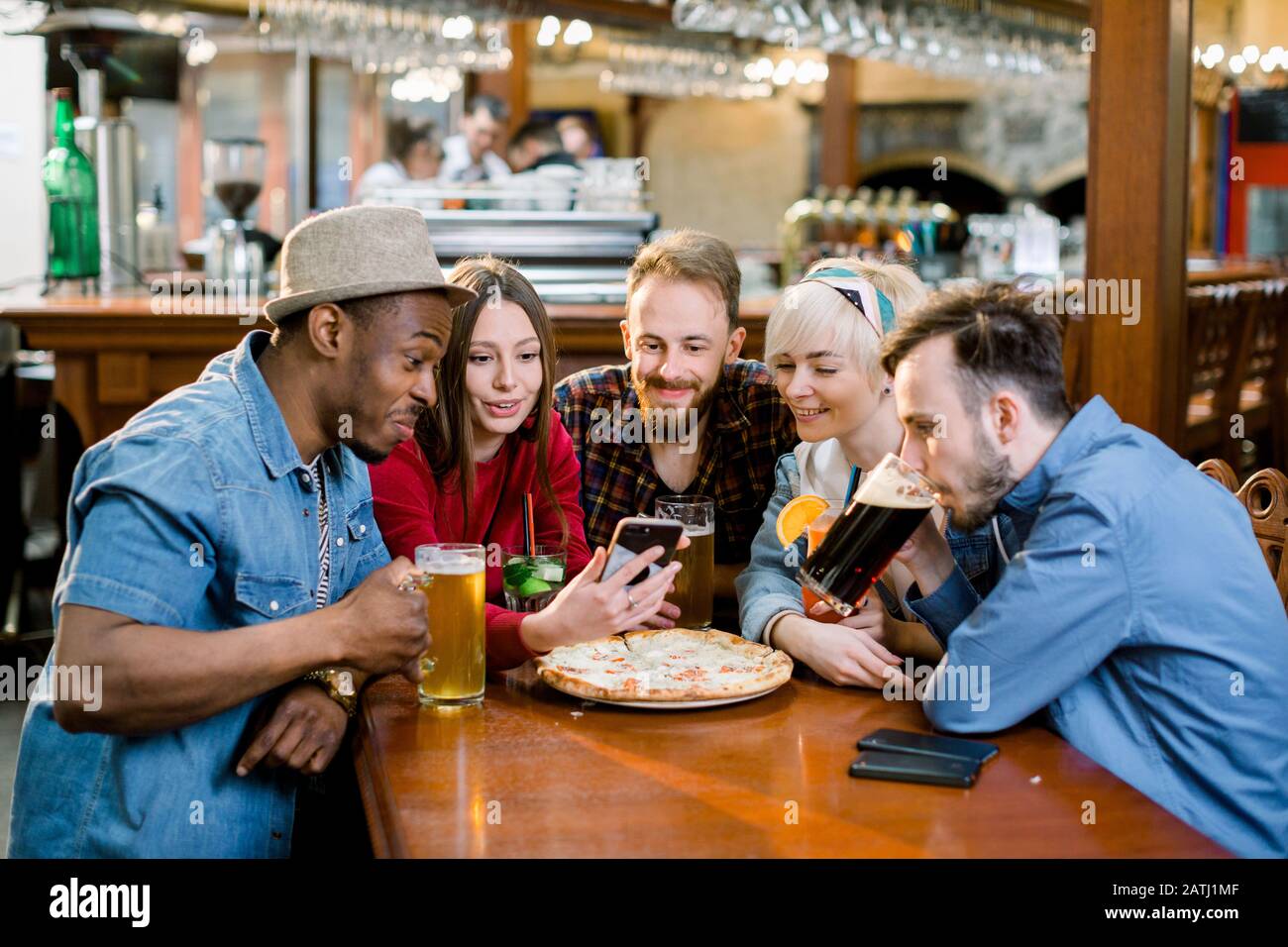 Group of young cheerful friends are sitting in a cafe, eating, drinking ...