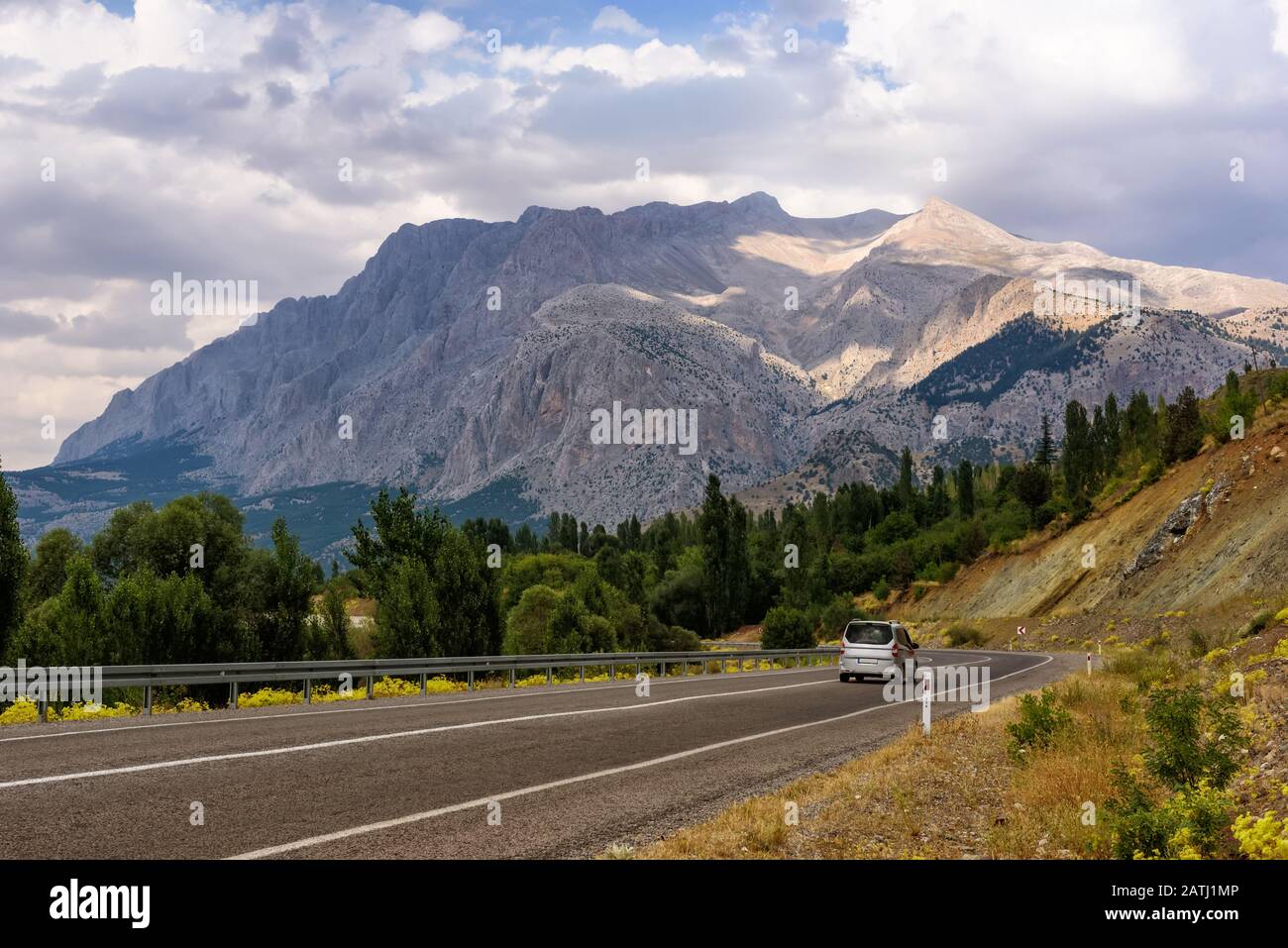 Panoramic view of the mountain with car on the road, forest and cloudy ...