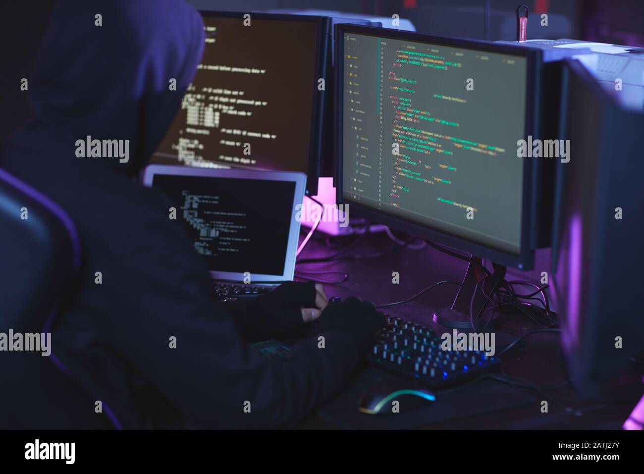 Back view of unrecognizable cyber security hacker wearing hood while ...