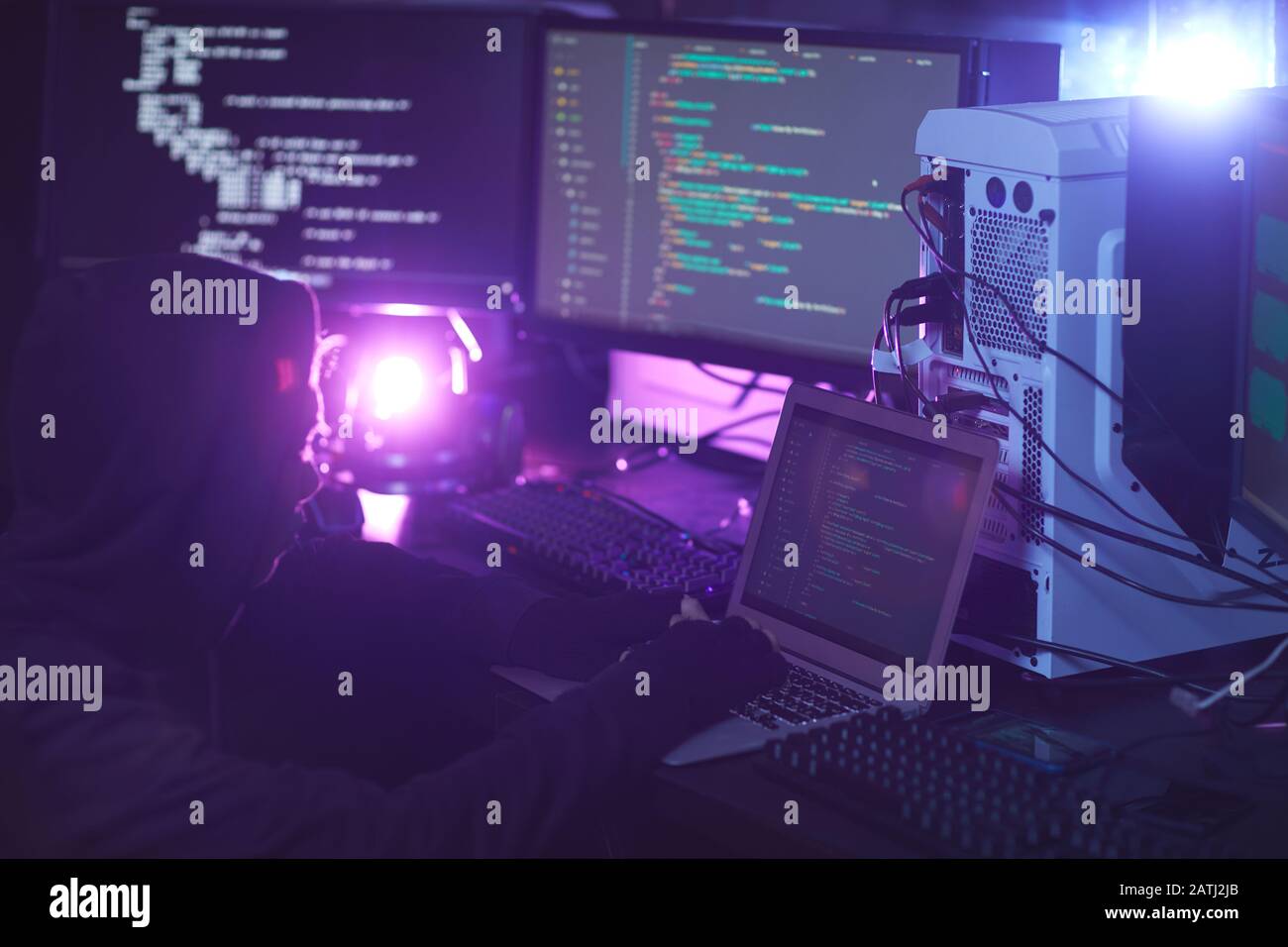 Side view at unrecognizable hacker using computer equipment with programming code on screens in ...