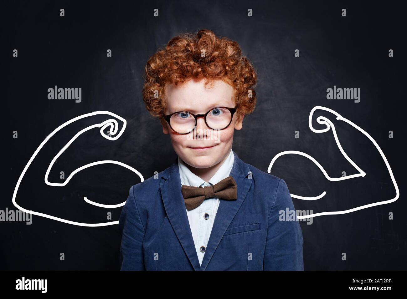 Strong child in blue suit, bow tie and glasses on chalkboard background ...