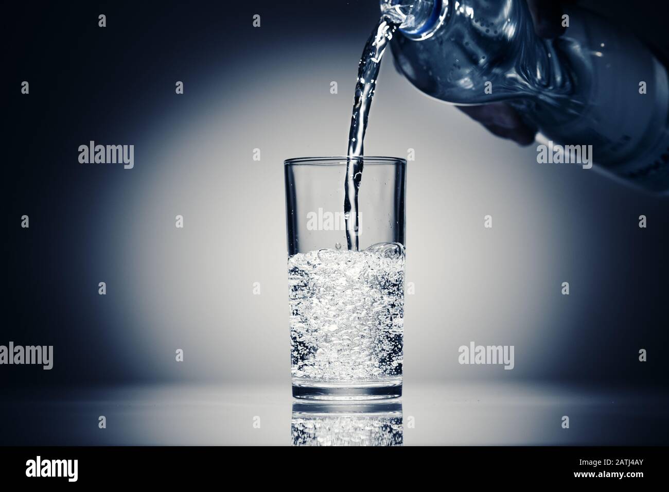 pouring sparkling water in a glass on a dark blue background Stock Photo - Alamy