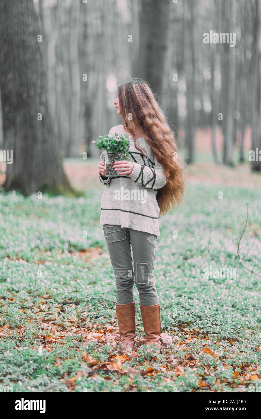 beautiful young girl woman walking through the green forest in spring ...