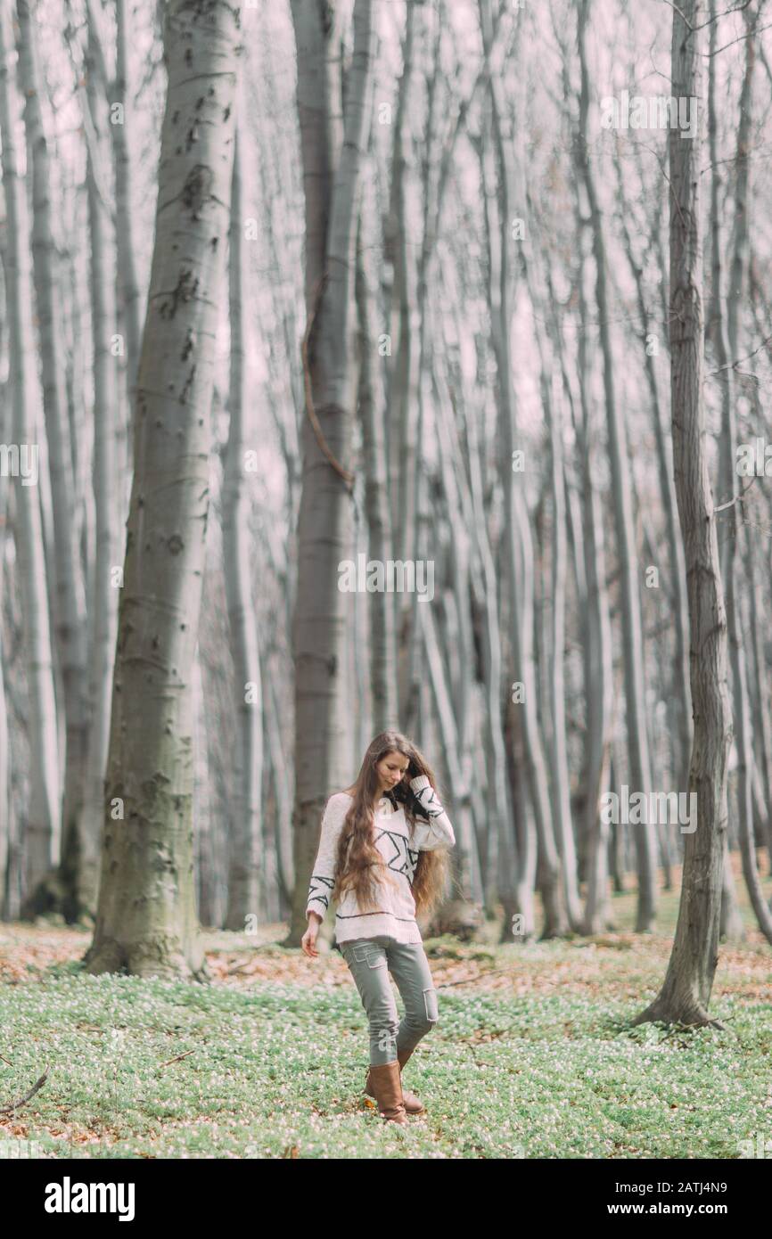 beautiful woman in white walking through the green forest in spring ...