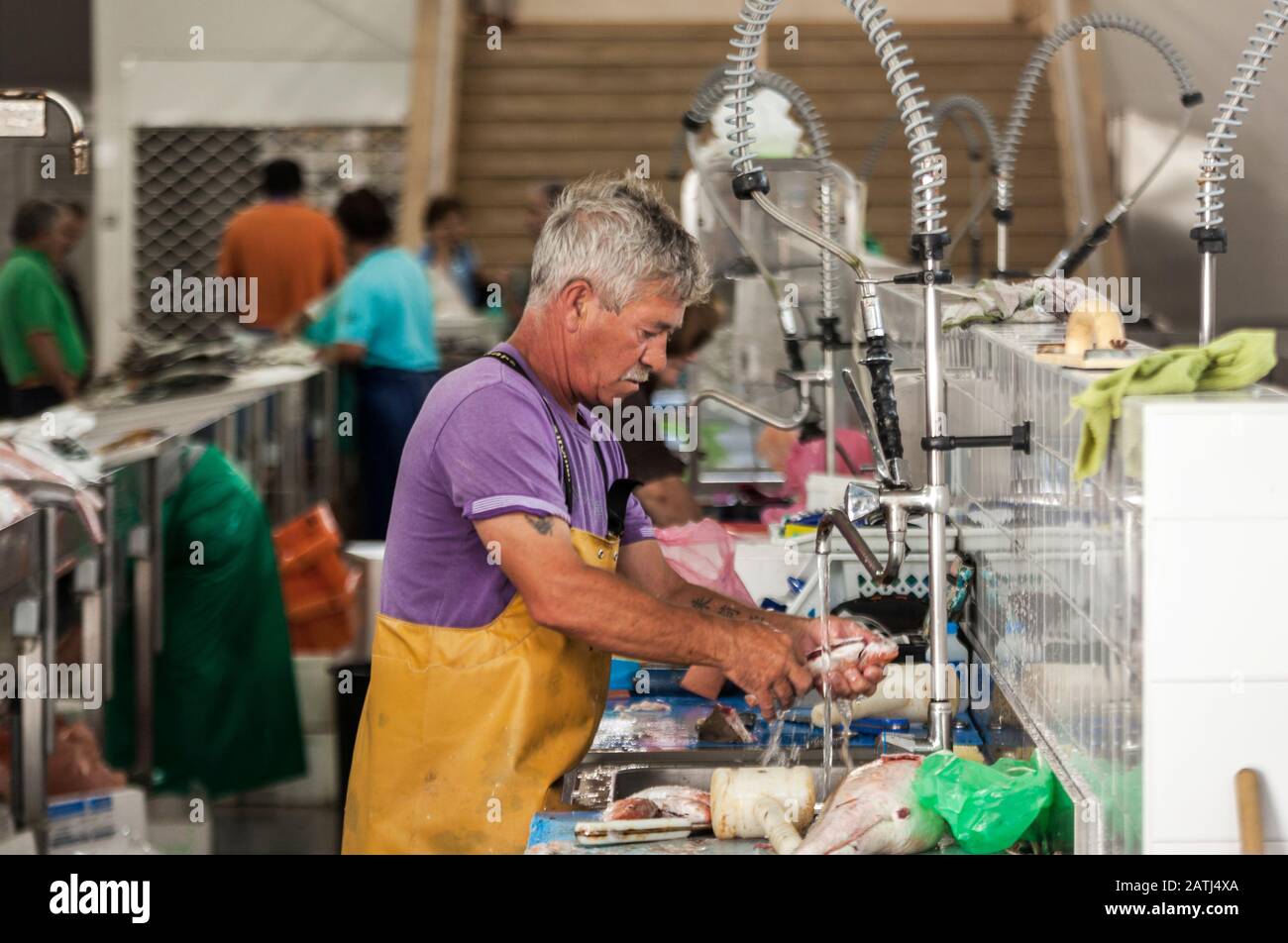 Fisherman washing fish at market Stock Photo - Alamy