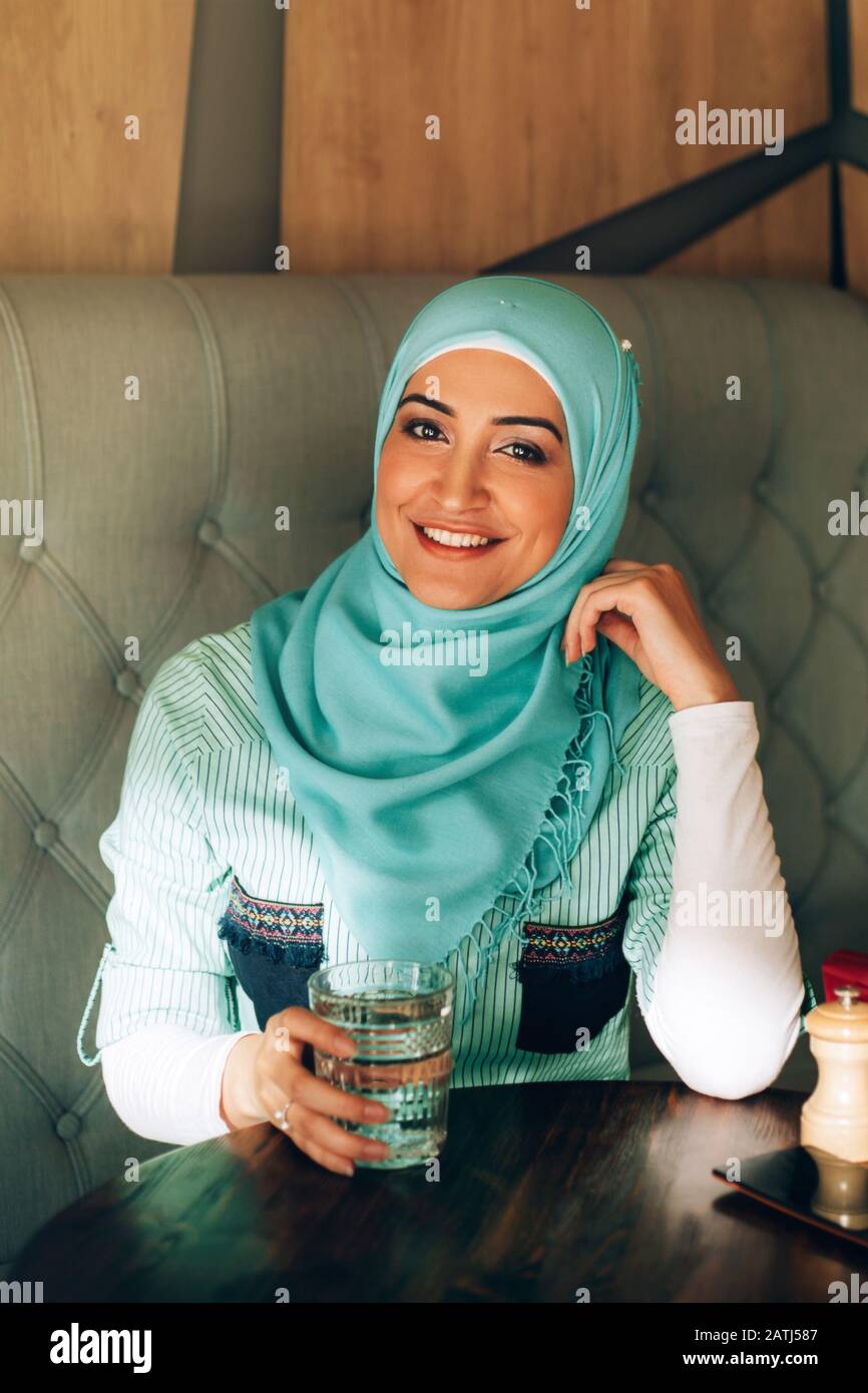 Beautiful Young Arabic Girl In Hijab Posing For Camera At Cafe With