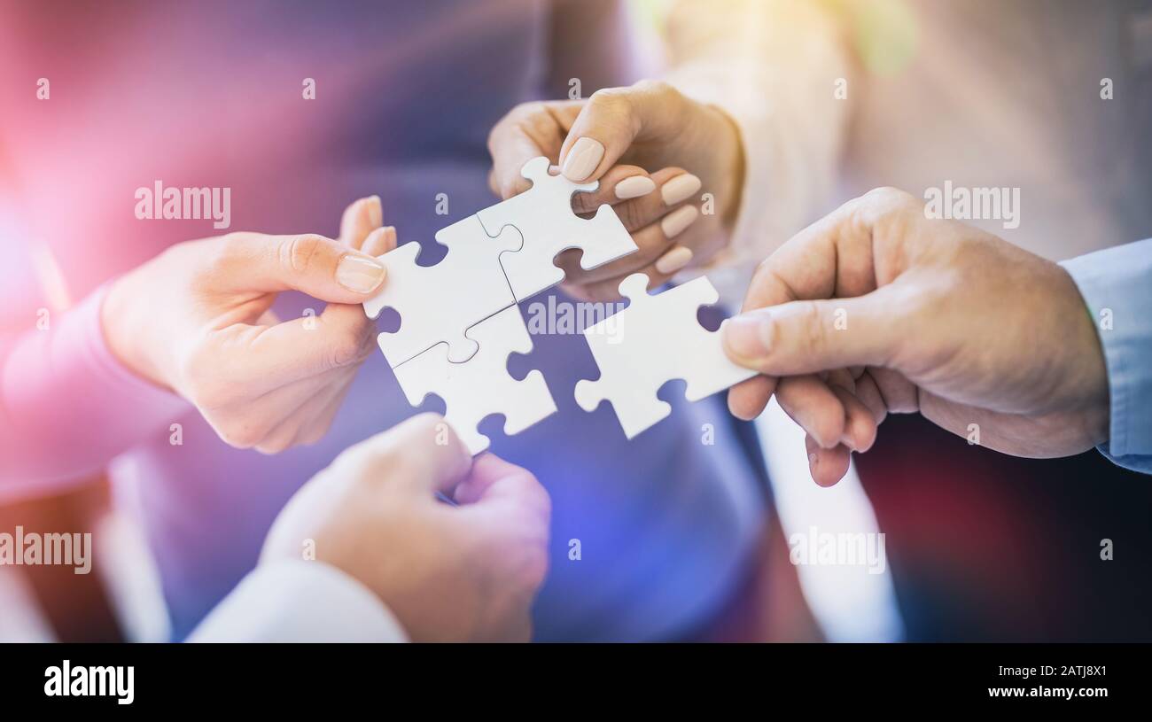 A group of business people assembling jigsaw puzzle. The concept of ...