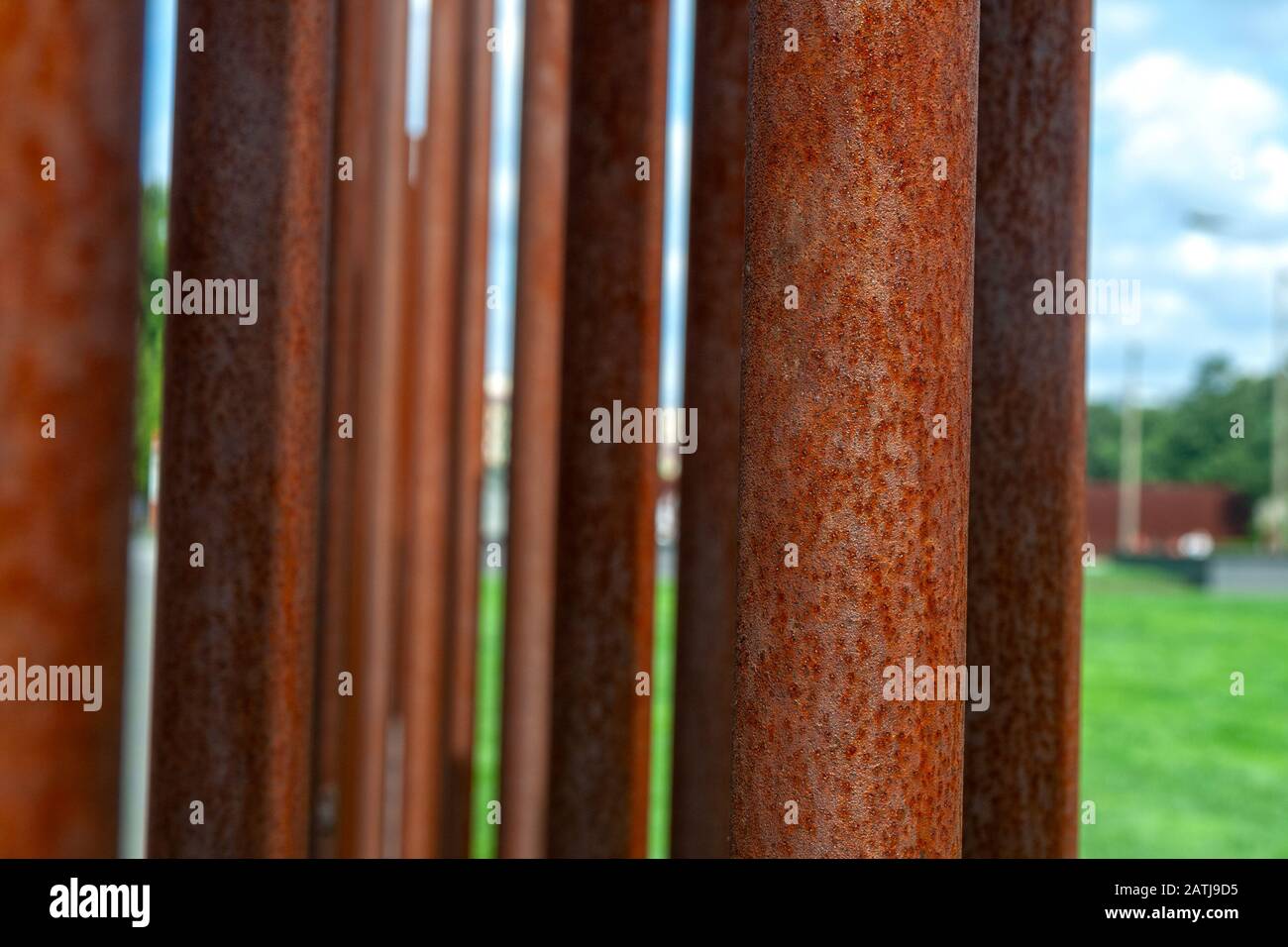 rusty iron bars close up in berlin wall and green grass background ...