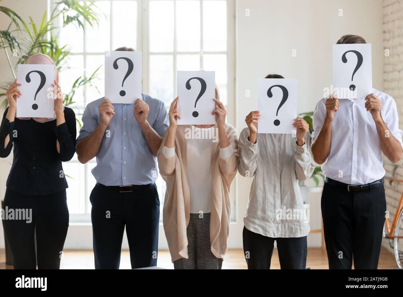 Diverse employees hide faces holding sheets with question marks Stock ...