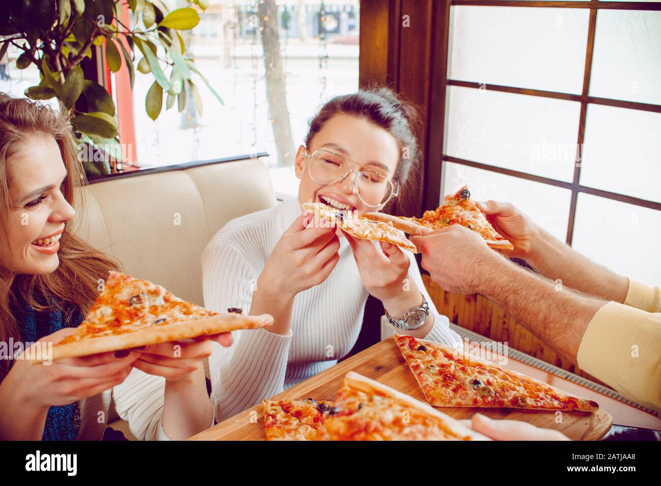 The company of guys in the pizzeria. Cheerful guys with pizza in their ...