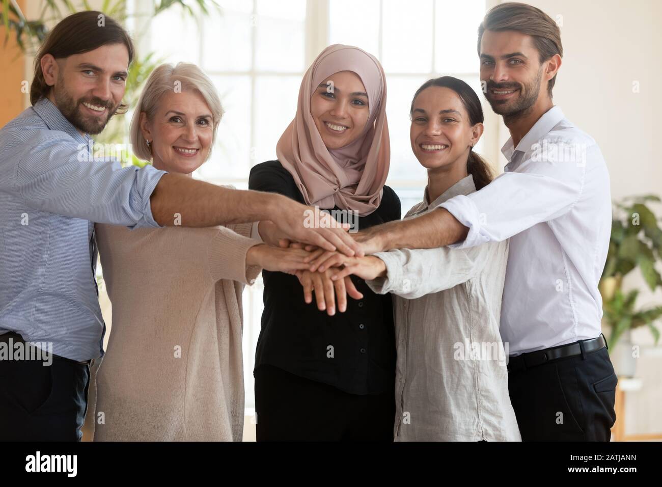 Portrait of smiling diverse employees stack hands together Stock Photo ...