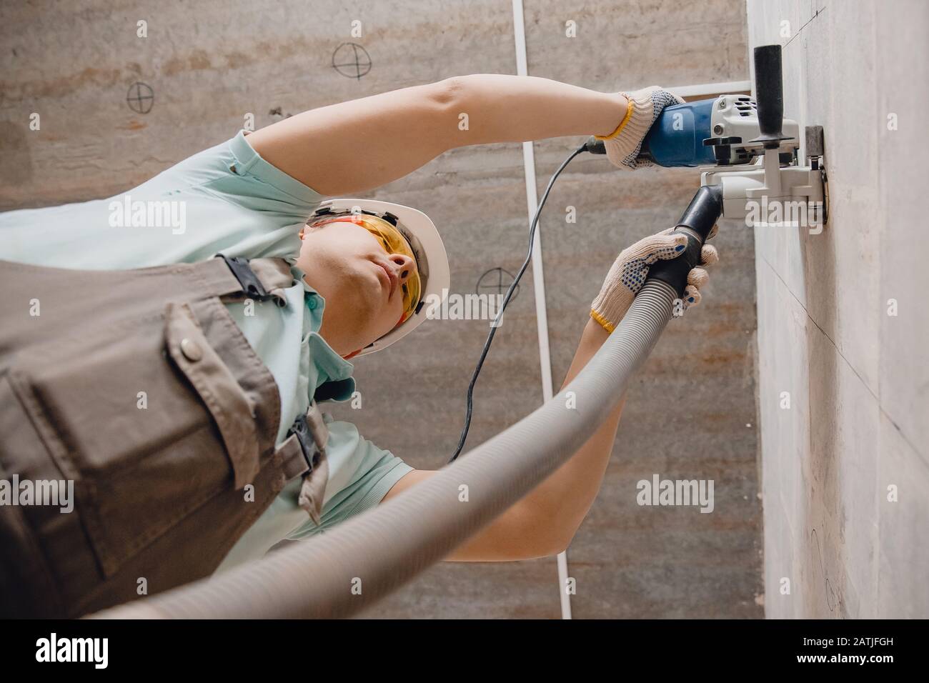 Builder worker cutting electrical chase in concrete wall with ...