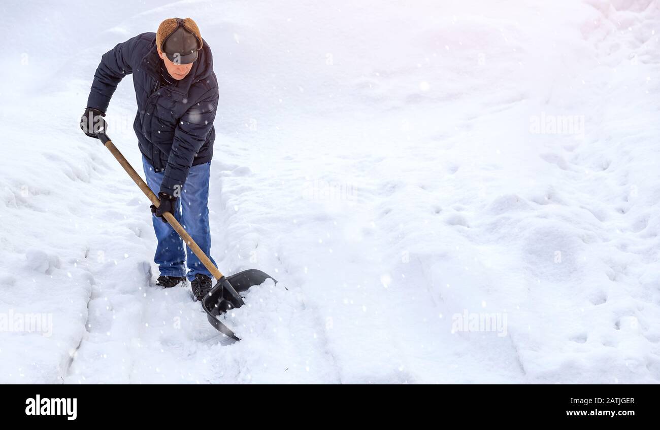 Man cleaning snow winter with shovel after snowstorm yard sunlight ...