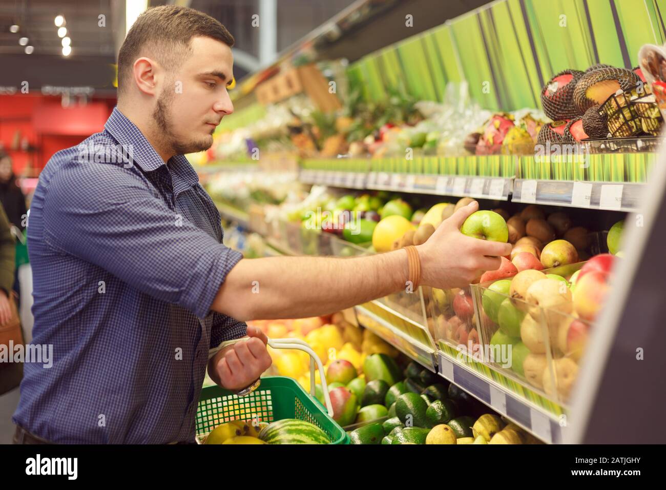 Man in a supermarket at the shelf for fruits shopping for groceries, he ...