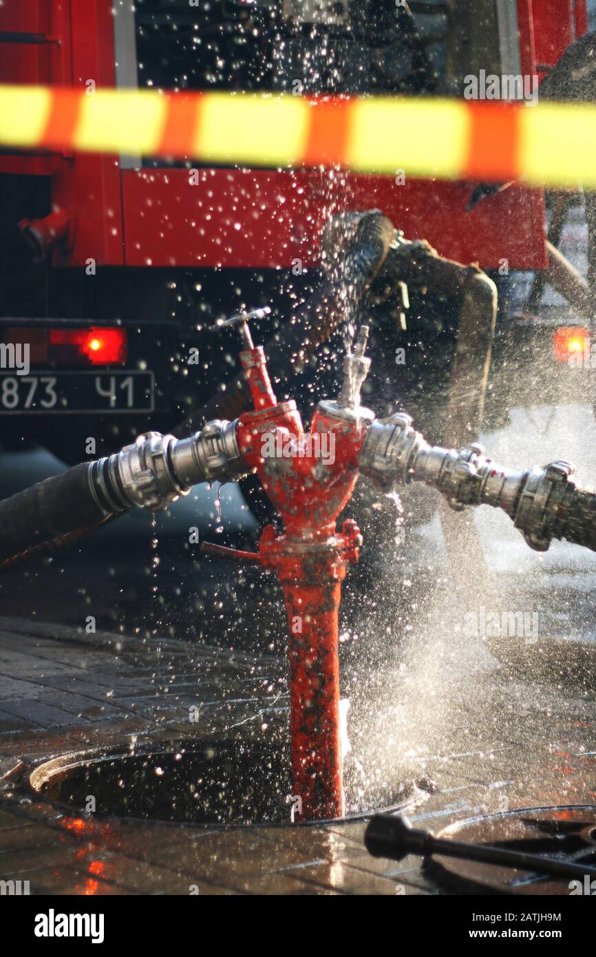 Water splashes from the fire hose and hydrant connections. Firefighters ...