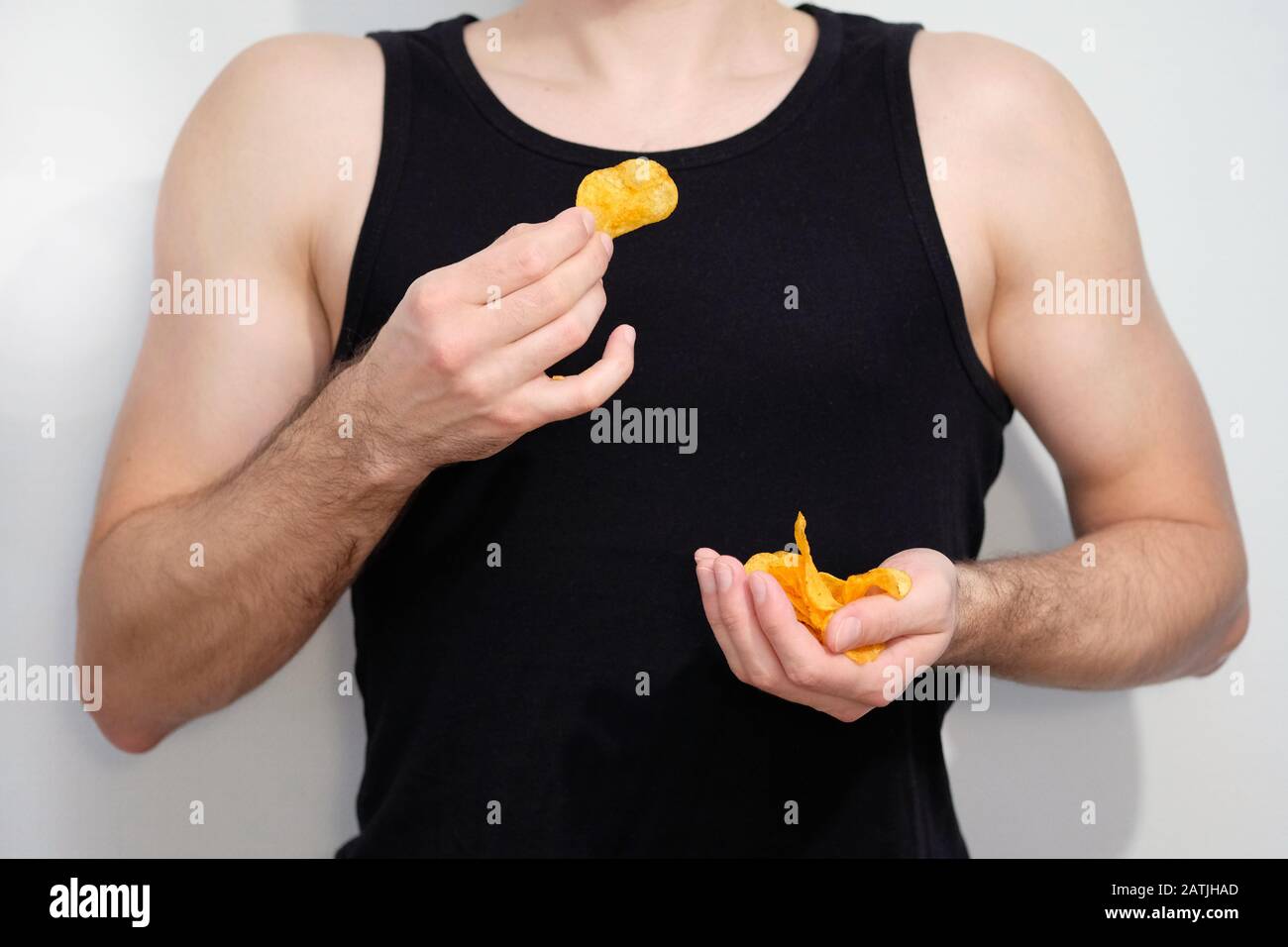 A guy in a black shirt holds chips in his hand. Torso and hands of a ...