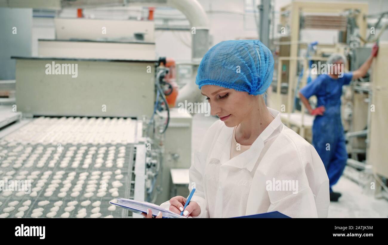 Candy factory. Controller checking conveyor with candies. Young woman ...