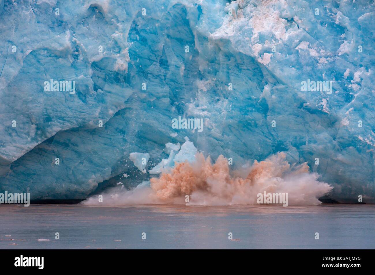 Huge ice chunk breaking from the edge of the Kongsbreen glacier calving into Kongsfjorden ...