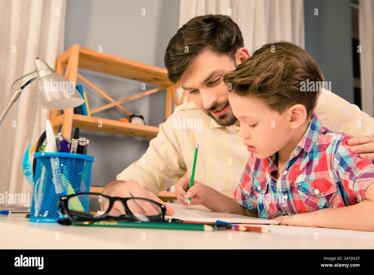 Happy family. Father and son doing homework together Stock Photo - Alamy