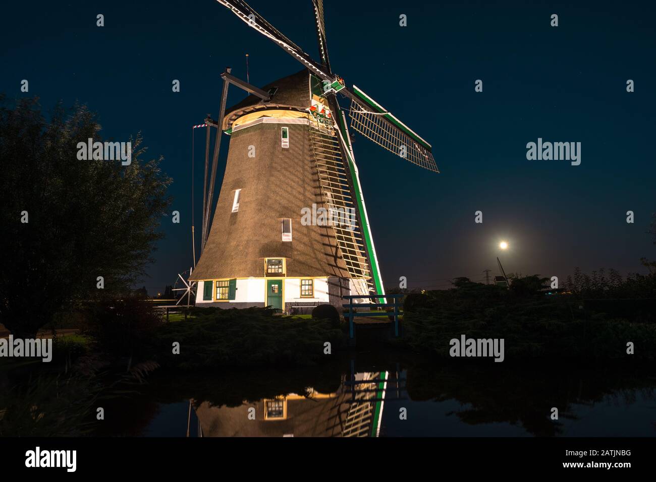 Traditional dutch windmill is illuminated at night. Rising full moon in ...