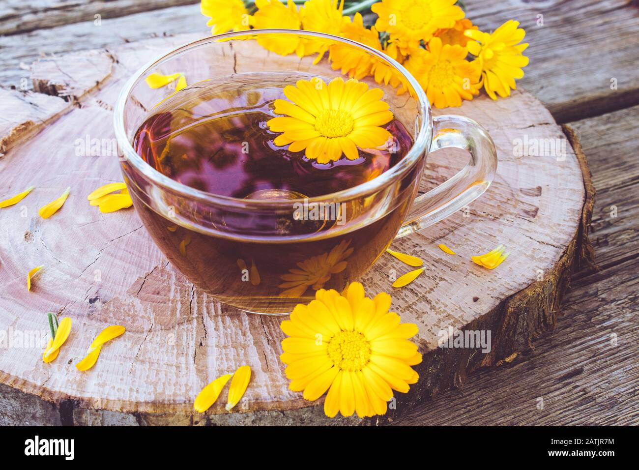 Herbal tea from calendula flowers in a transparent glass mug. Extract ...