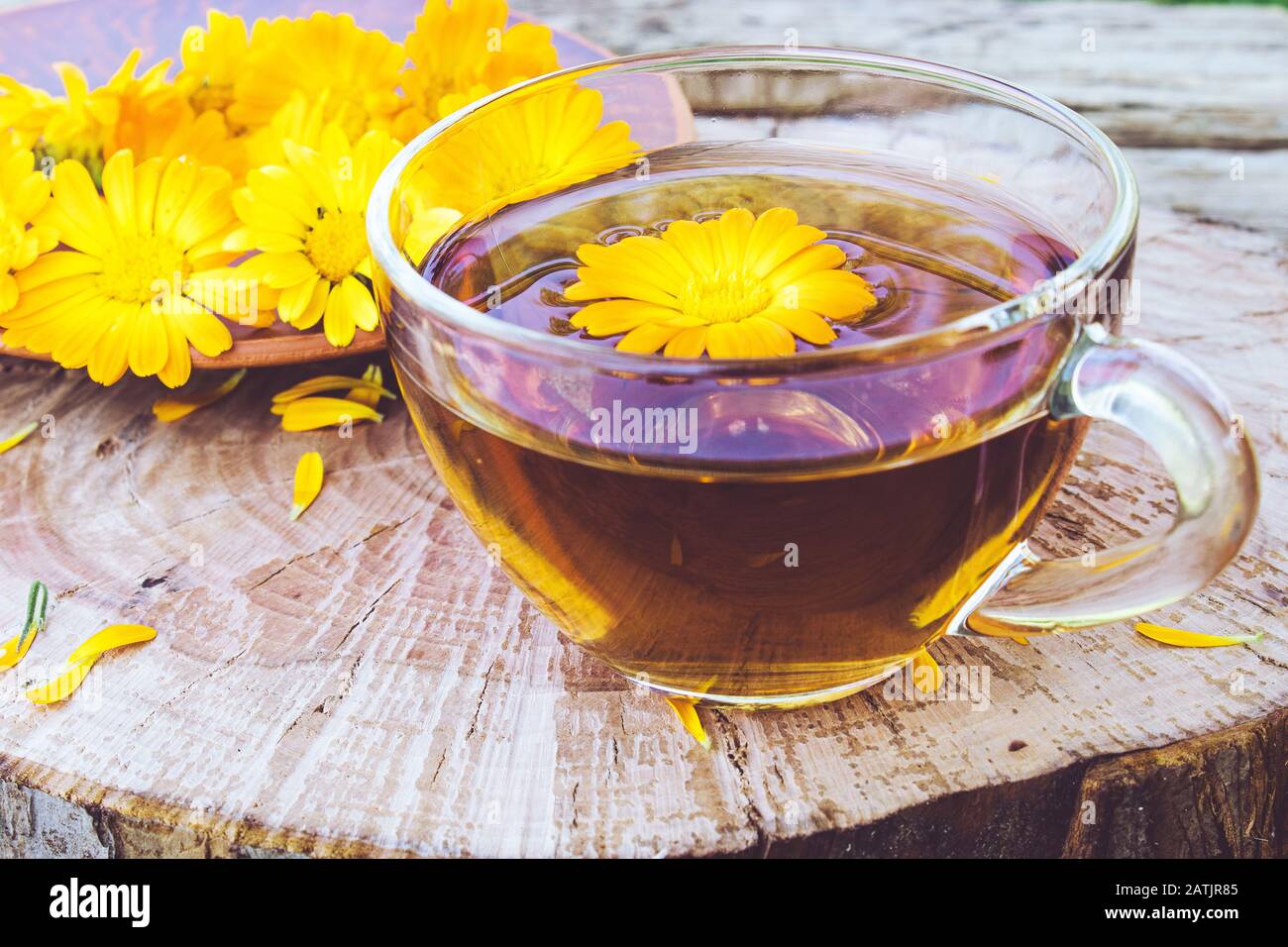 Herbal tea from calendula flowers in a transparent glass mug. Extract ...