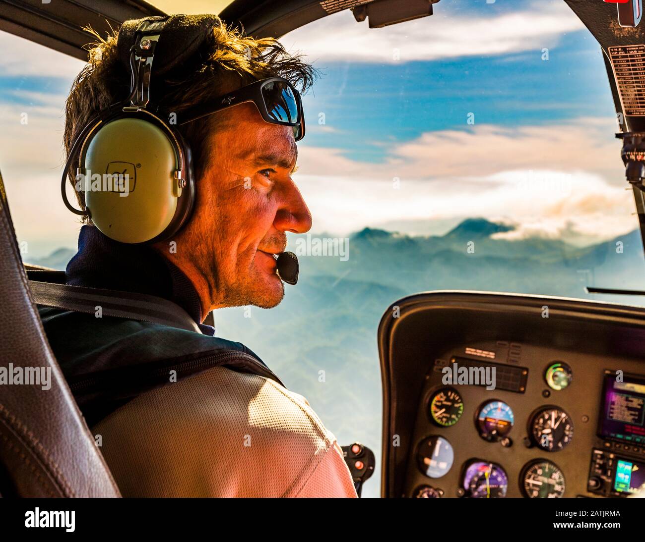 Helicopter pilot in his cockpit in front of the volcanoes of Bougainville, Papua New Guinea ...