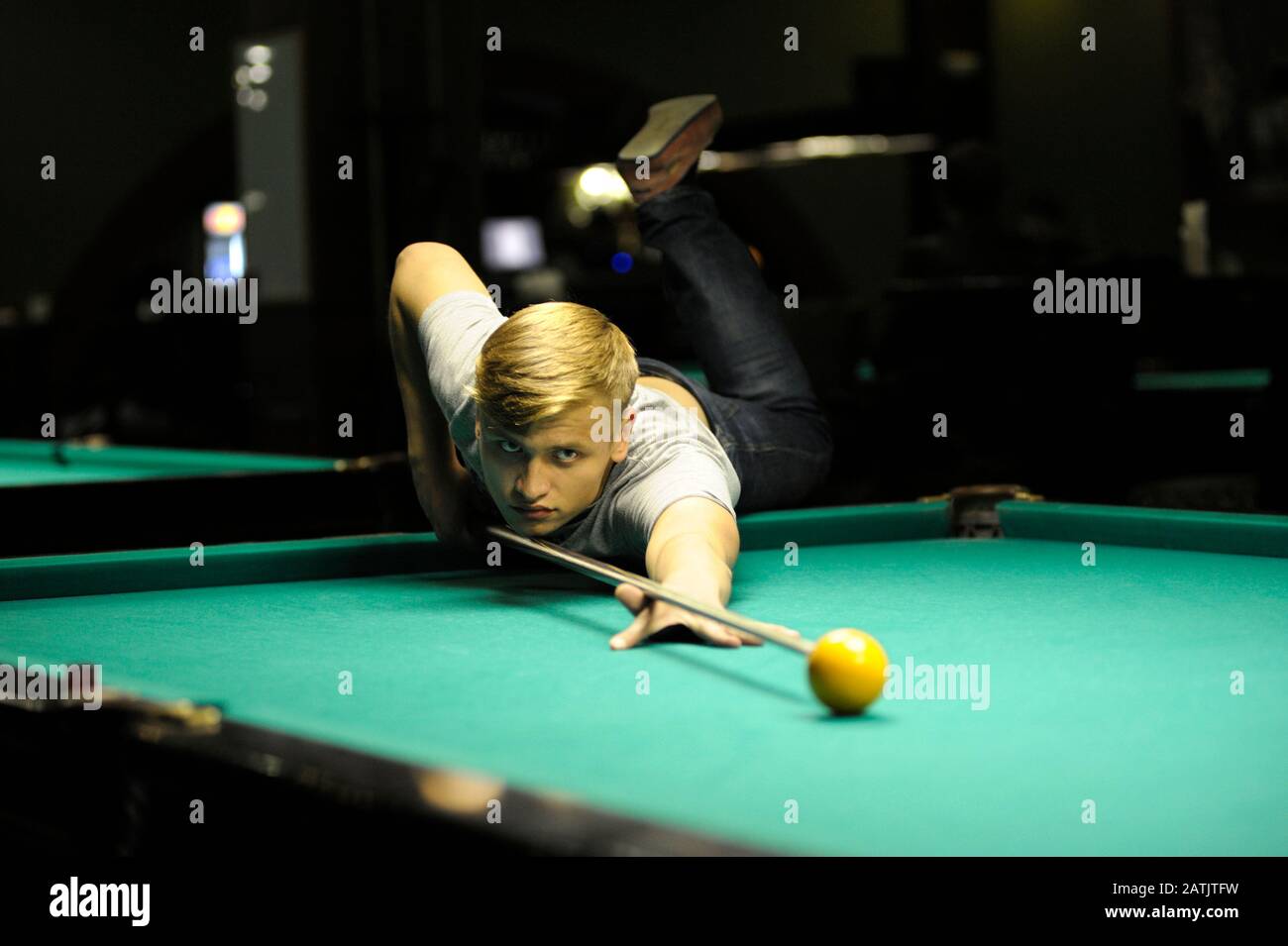 Male billiard player gets ready to stroke a ball with cue stick using a ...