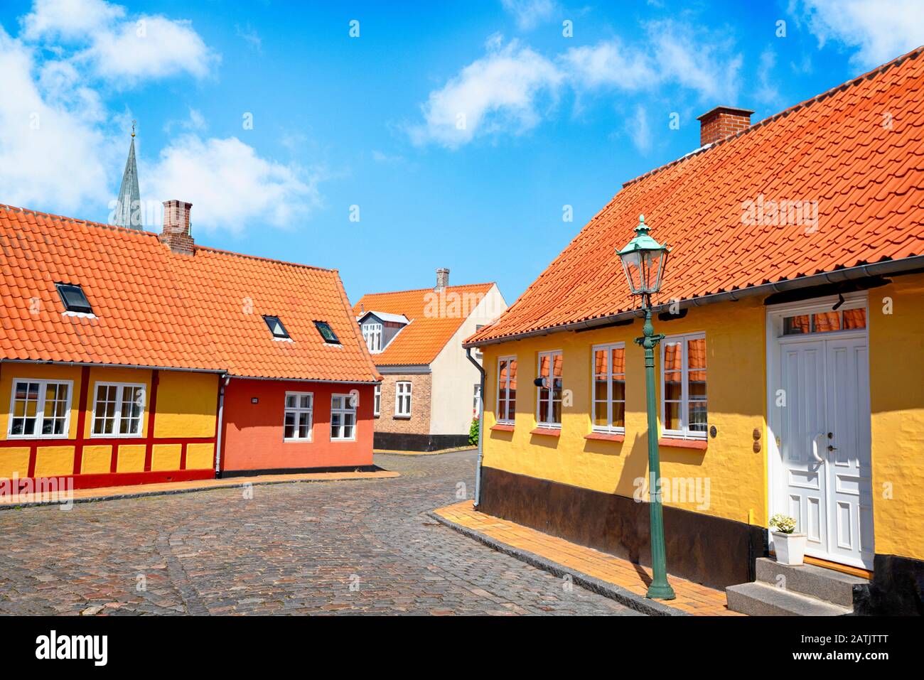 Street with yellow buildings and cooblestone on the road under a blue ...
