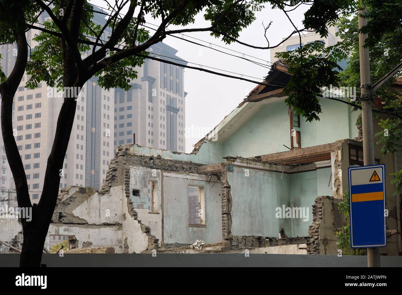 Destroyed building in Chinese city, modern construction in background ...