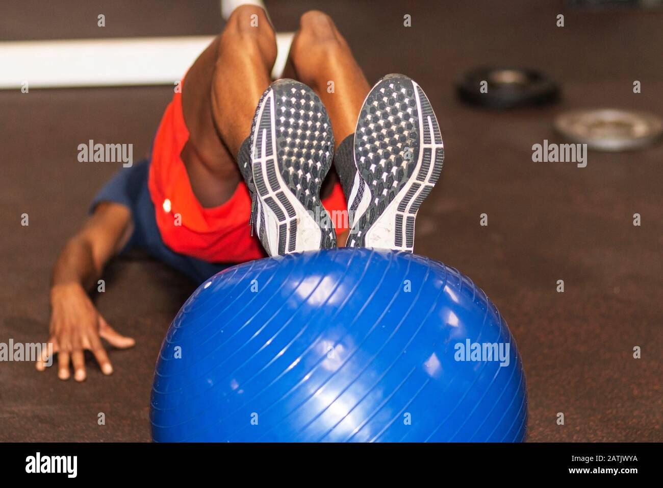 An African American male runner is lying on the floor of a gym with his ...