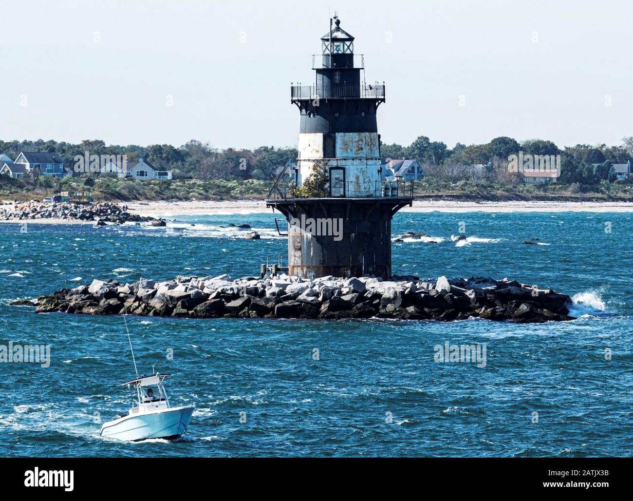 A boat is passing the Orient Point Lighthouse on a windy day with rough ...