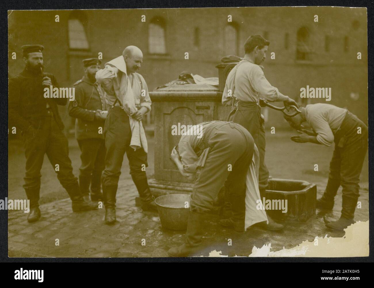 Description: German soldiers wash at a pump in the courtyard of a ...