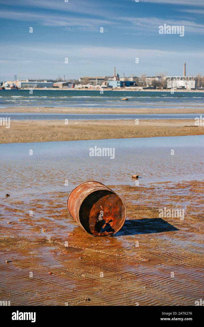 A water pollution scene in nature with an old rusty oil barrel dropped ...