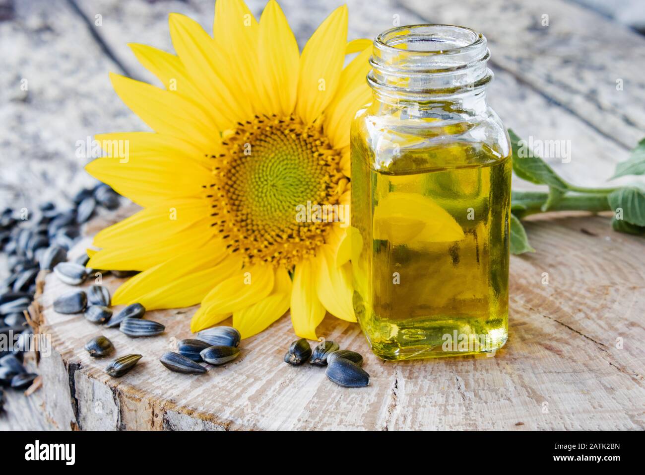 Sunflowers and seeds on a wooden background near sunflower oil in a ...