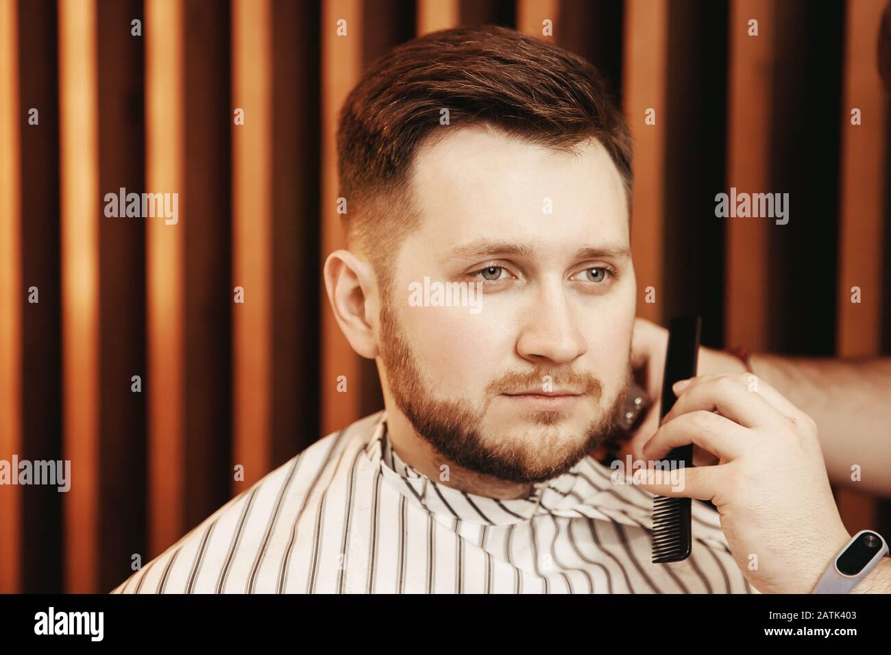 Barber shaves his beard to hipster man in barbershop. Toned photo ...