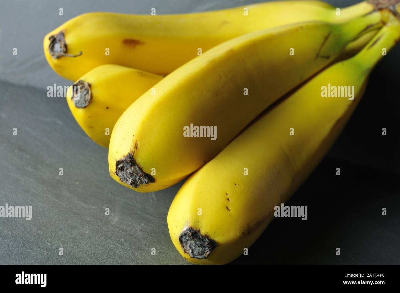 bunch of yellow bananas lying on a plate of gray slate Stock Photo - Alamy