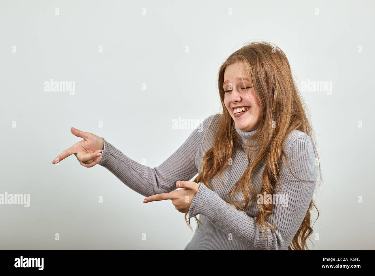 red-haired woman in a gray sweater smiles points index finger in the ...