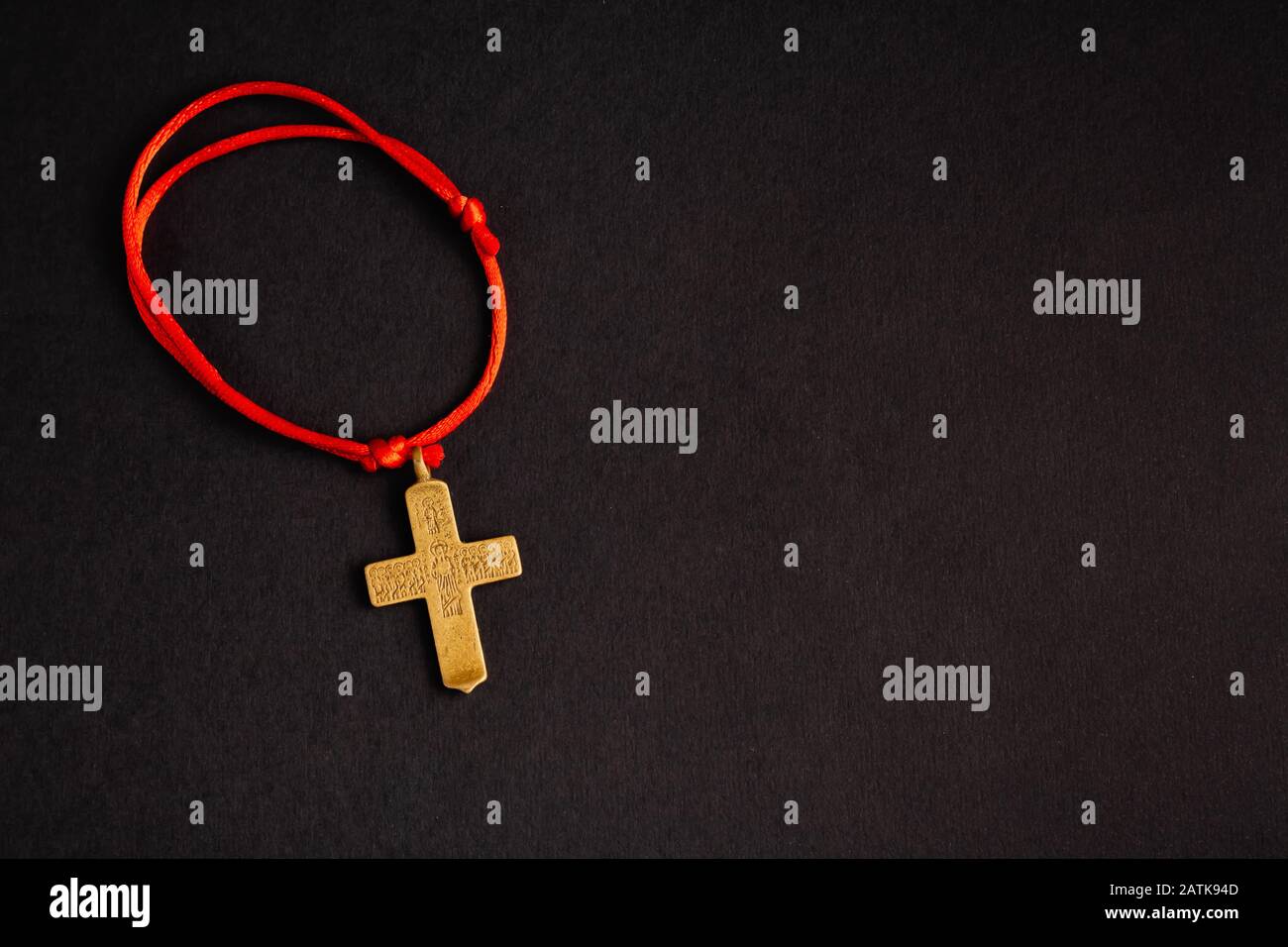 Christian cross on a red rope, on a black background with an empty ...