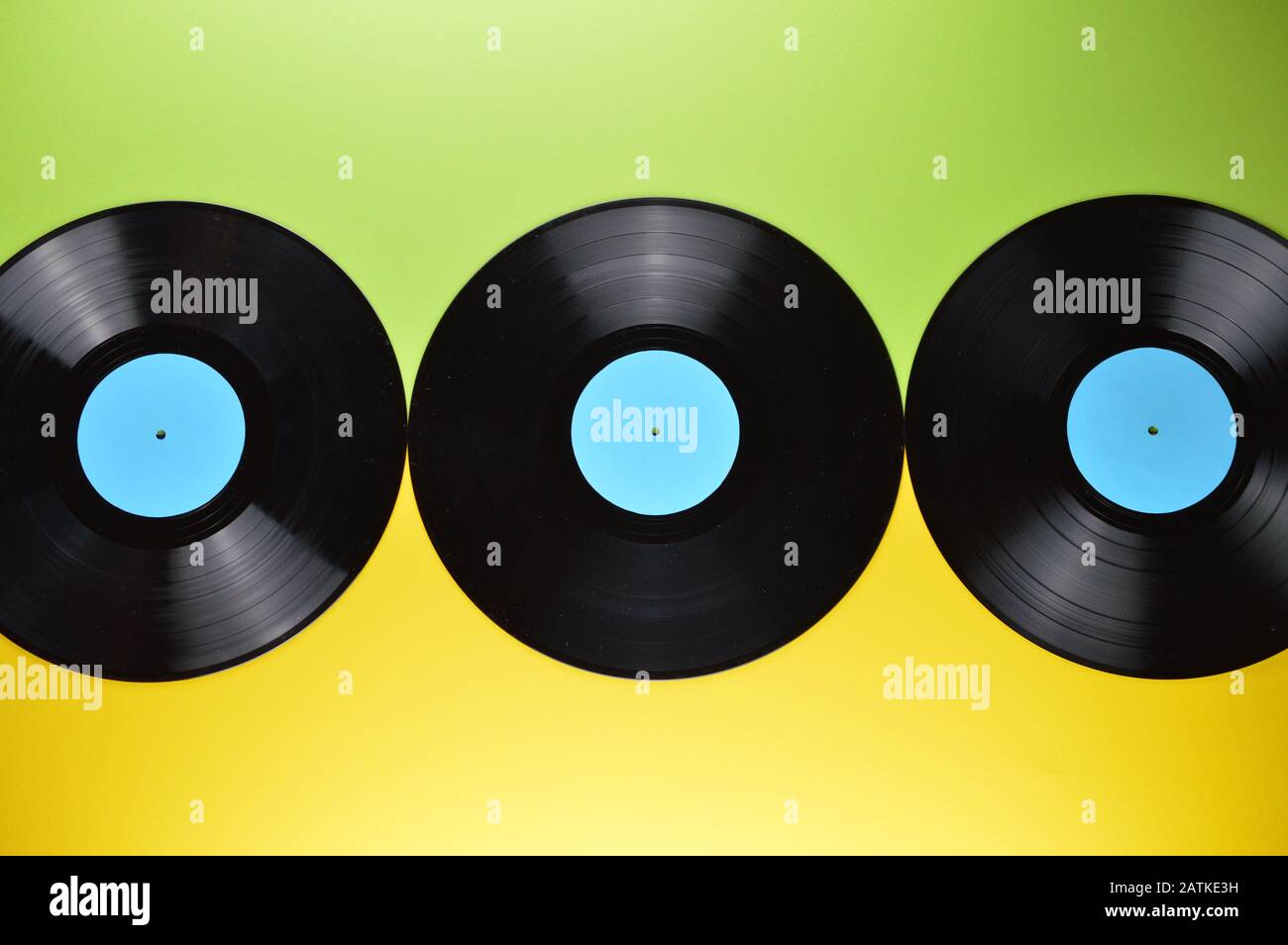 three old black vinyl records with blank cyan labels on yellow and ...