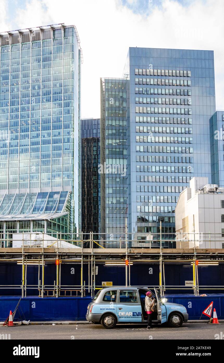 A lady taxi driver gets into her taxi which is parked in front of ...