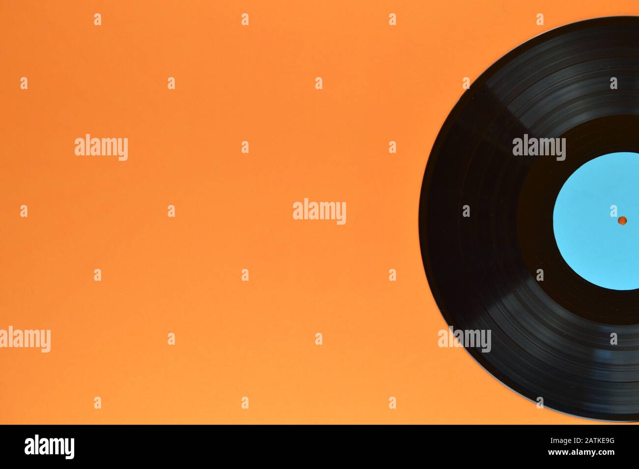 old black vinyl record with blank cyan label half on orange background ...
