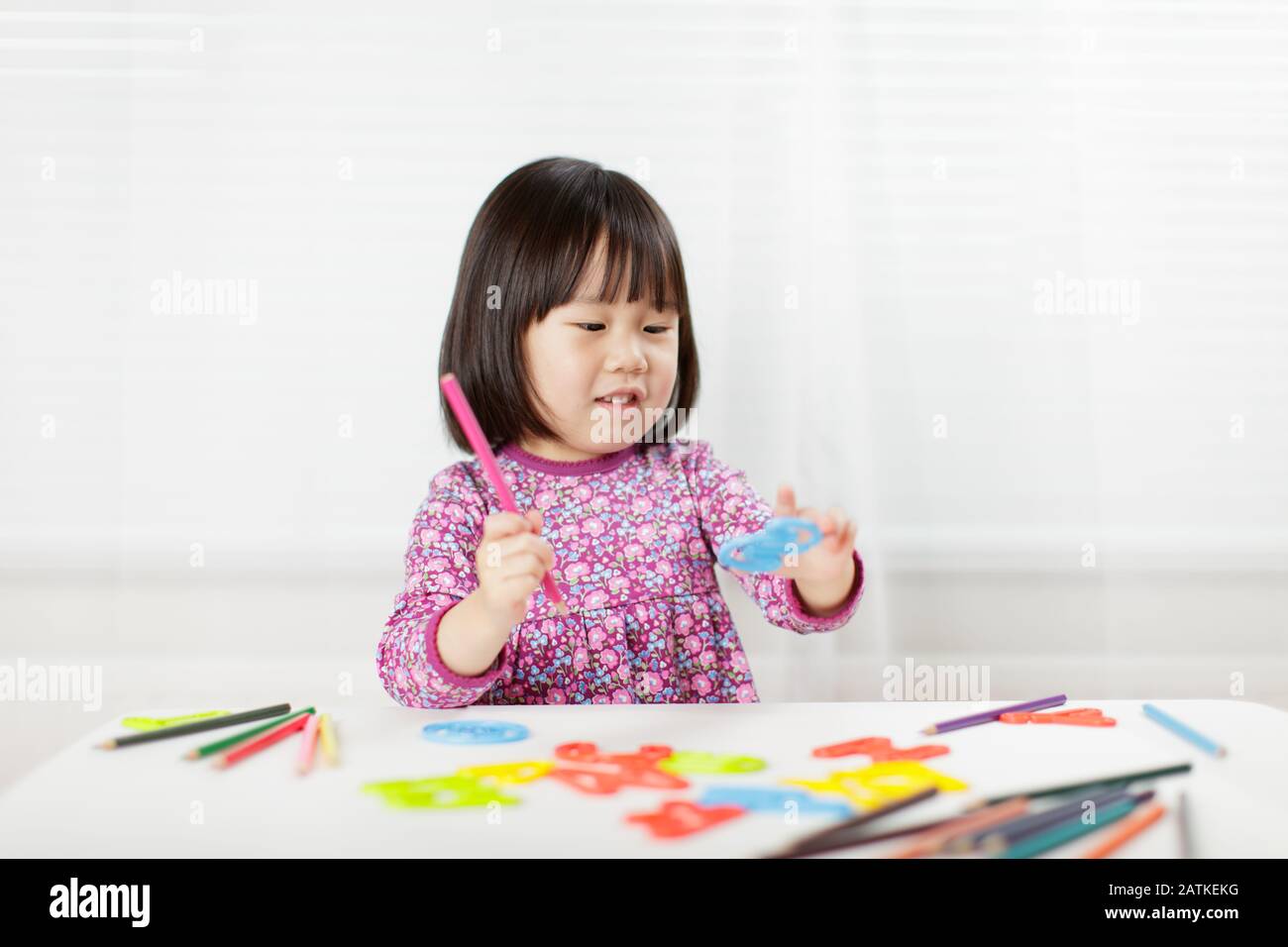 toddler girl practice writing letters on white paper against white ...
